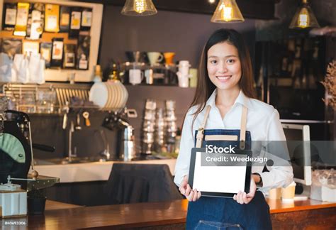 아시아 여자 바리 스타 커피숍 카운터 바 앞 빈 태블릿 컴퓨팅을 들고 웃 고 메뉴 또는 화면에 경로 클리핑 하는 디자인의 디스플레이 대 한 공간을 조롱 태블릿에 대한 스톡