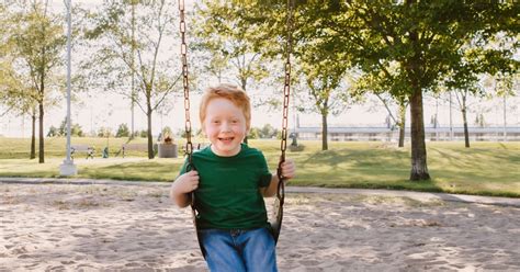 행복한 미소를 짓는 작은 미취학 아동은 여름날 바깥 그네 놀이터에서 그네를 타고 있습니다 행복한 어린 시절 생활 방식 개념입니다 어린이를 위한 계절 야외 활동 사진