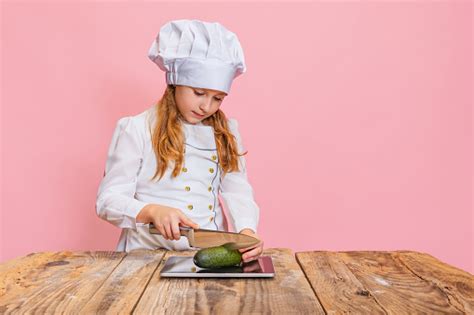 흰색 요리사 유니폼과 분홍색 스튜디오 배경에 고립 된 신선한 야채를 절단 거대한 요리사의 모자를 입은 어린 소녀 6 7 살에 대한 스톡 사진 및 기타 이미지 Istock