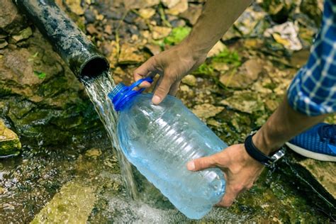 Premium Photo A Person Collects Clean Water From A Spring In A