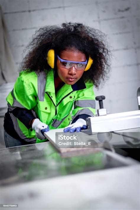 곱슬 머리를 가진 아프리카 산업 여성 노동자는 안전 조끼와 보호 헤드폰을 착용하고 목재 절단기로 작업하며 여성 엔지니어는 Cnc 목공 제조 가구 공장에서 일합니다 20 24