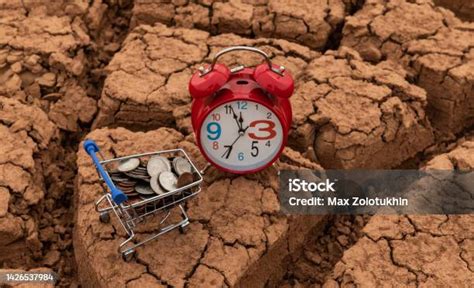 사막에서 금이 간 점토의 배경에 동전과 빨간 알람 시계가있는 쇼핑 트롤리 0명에 대한 스톡 사진 및 기타 이미지 0명 가뭄 개념 Istock