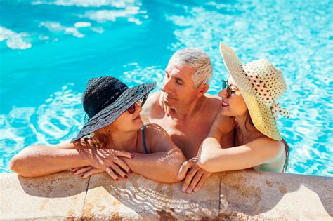 호텔 수영장에서 성인 딸과 함께 휴식을 취하는 선임 가족 커플 리조트에서 휴가를 즐기는 사람들 25 29세에 대한 스톡 사진 및