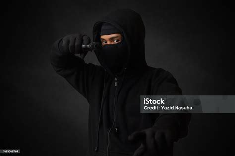 검은 후드티와 마스크를 쓰고 권총을 들고 총을 쏘는 수수께끼의 남자 어두운 주변 배경에 격리된 이미지 20 24세에 대한 스톡 사진 및 기타 이미지 Istock