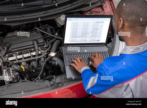 Young Male Mechanic Using Laptop While Examining Car Engine Stock Photo ...