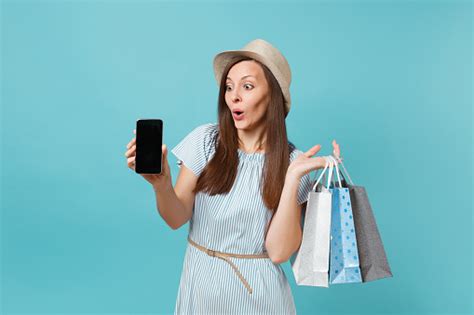 여름에 여자의 초상화 드레스 밀 짚 모자 블루 파스텔 배경에서 분리 하는 빈 화면으로 쇼핑 모바일 핸드폰 후 구입 패키지 가방을 들고 광고에 대 한 공간을 복사 합니다