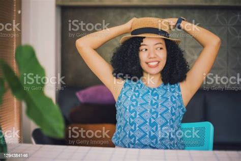 행복한 아시아 검은 곱슬 머리 여자는 모자를 쓰고 집 배경에 앉아 생각하고 35 39세에 대한 스톡 사진 및 기타 이미지