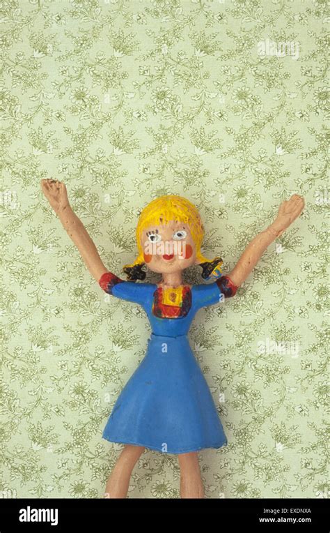 Bendy Rubber Girl Doll With Blue Dress And Innocent Expression Standing With Arms Raised In