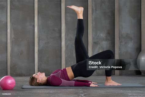 운동복을 입은 젊은 여성이 한쪽 다리를 들어 엉덩이 다리를 수행합니다 필라테스 스튜디오 볼기근에 대한 스톡 사진 및 기타 이미지 볼기근 운동 수업 25 29세
