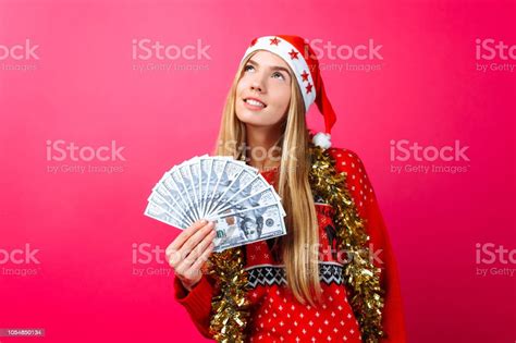 꿈꾸는 소녀 빨간 스웨터와 산타 클로스의 모자 계획 하 고 생각 어디에 돈을 지출 빨간색 배경에 돈을 유지 합니다 감탄에 대한