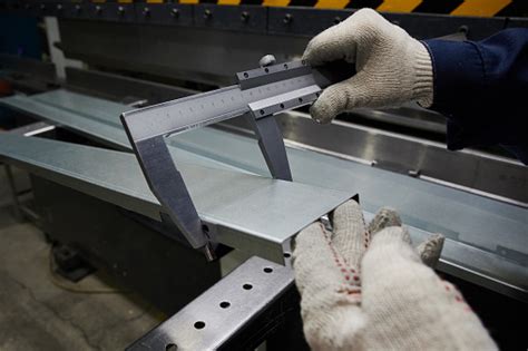 공장의 전문가는 주니어 캘리퍼와 함께 컬벡터 타입의 산업용 라디에이터의 커버로 사용되는 금속판의 굽힘 정확도를 측정하고 생산 라인의 품질 관리 강철에 대한 스톡 사진 및