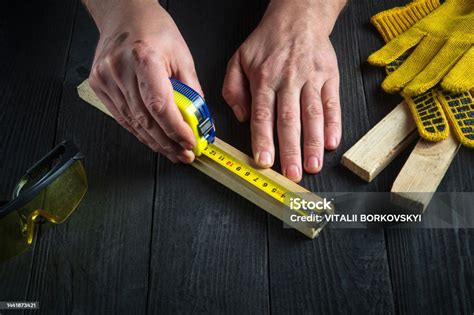 목수 또는 목공인은 건설 테이프를 사용하여 나무 조각의 길이를 측정합니다 직장에서 주인의 손 클로즈업 목공 작업장의 작업 환경