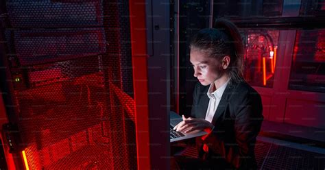 심각한 백인 여성 엔지니어가 서버 장비 옆에 웅크리고 노트북을 사용하는 동안 빨간불로 켜진 서버실에서 문제를 해결합니다 사진 Unsplash의 데이터 이미지