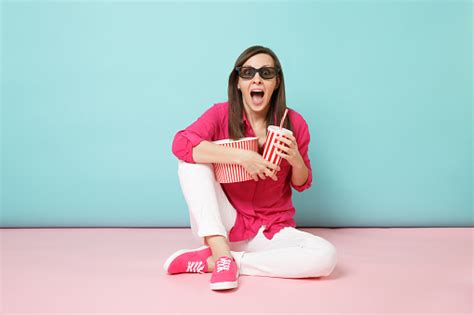 전체 길이 세로 재미 여자 장미 셔츠에서 흰색 바지 밝은 핑크 블루 파스텔 벽 배경 스튜디오에 고립 된 보고 영화 필름을 바닥에 앉아 패션 라이프 스타일 개념입니다 복사