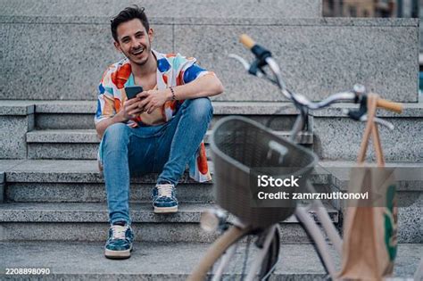 스마트 폰과 자전거를 가진 젊은이가 도시의 계단에 앉아 있습니다 20 29세에 대한 스톡 사진 및 기타 이미지 20 29세 30 34세 Brand Name Smart