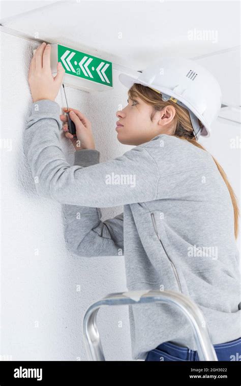 Woman Fitting An Exit Sign Stock Photo Alamy