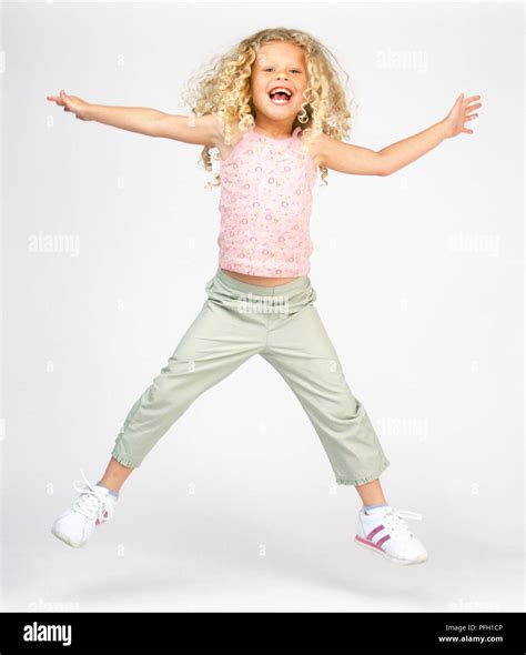 Girl Jumping In Air With Legs Apart And Arms Spread Wide Front View