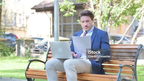 중년 사업가가 야외에서 문서와 노트북 작업을 하고 있다 40 49세에 대한 스톡 사진 및 기타 이미지 40 49세 계약서 남자 사업가 Istock