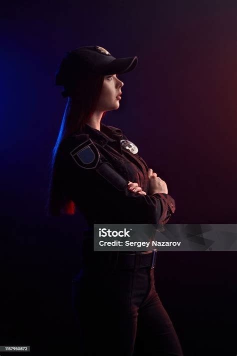 심각한 여성 경찰관은 빨간색과 파란색 백라이트와 검은 배경에 대한 카메라를 위해 포즈를 취하고있다 검은색에 대한 스톡 사진 및 기타 이미지 Istock