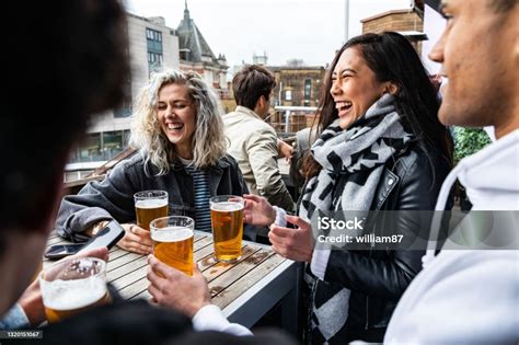 펍 양조장에서 함께 맥주를 즐기는 사람들 행복한 웃음 남자와 여자가 이야기하고 파인트 유리를 들고 런던의 라이프 스타일과 음료