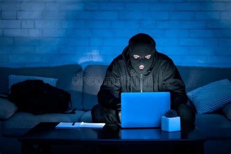 Masked Hacker Downloading Private Information Off A Computer Stock