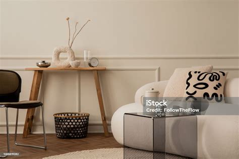 하얀 소파 유리 커피 테이블 나무 벤치 말린 꽃이 있는 베이지색 꽃병 무늬가 있는 베개 검은색 의자 및 개인 액세서리가 있는 거실 인테리어의 아늑한 구성 가정 장식 템플렛