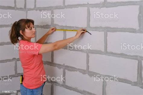 한 여성이 새 아파트에서 벽의 길이를 측정합니다 수리 작업을 위한 거리 측정 집안의 공간을 측정하는 측정 테이프가 제작되었습니다 3차원 형태에 대한 스톡 사진 및 기타
