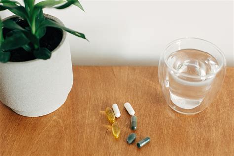 식이 보조 제 오메가 3 스피룰리나 엽록소 마그네슘 캡슐 및 나무 테이블에 물 한 잔 아침 비타민 알약 건강 지원 및 치료 생물학적 활성 첨가제 0명에 대한 스톡 사진 및