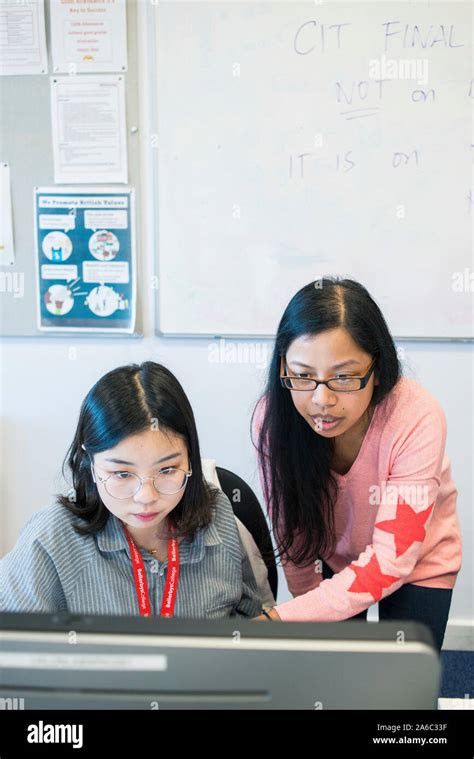 A Computer Technology Class With Students Working And Helping Each