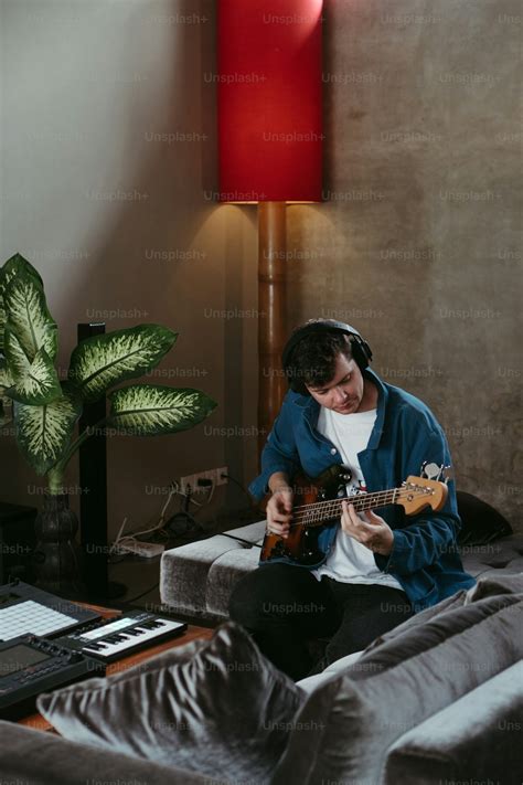소파에 앉아 기타를 연주하는 남자 사진 Unsplash의 전자공학 이미지