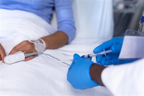 Premium Photo Midsection Of African American Male Doctor Giving Iv Injection To Female Patient