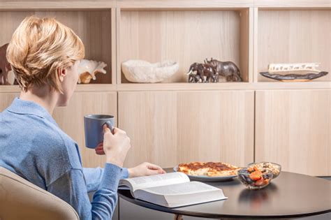 종이 책과 차 한 잔을 손에 든 여성이 티 테이블에서 읽습니다 50 54세에 대한 스톡 사진 및 기타 이미지 50 54세 가정 생활 가정의 방 Istock