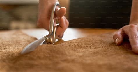 여성 장인이 가위로 갈색 가죽을 자르는 것을 닫습니다 사진 Unsplash의 브라운 레더 이미지