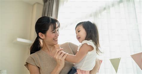 아시아의 아름다운 사랑하는 어머니는 어린 여자 딸을 팔에 안고 빙글빙글 돌고 있습니다 매력적인 부모는 어린 작은 소녀와 미소