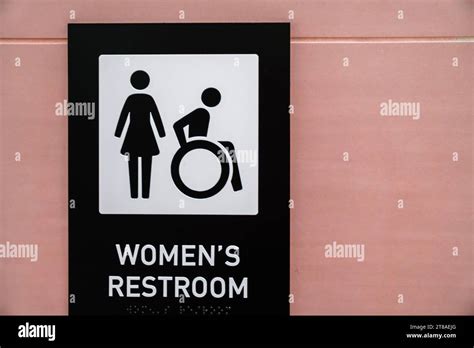 Close Up Of Womens Bathroom Sign Against Pink Colored Wall With