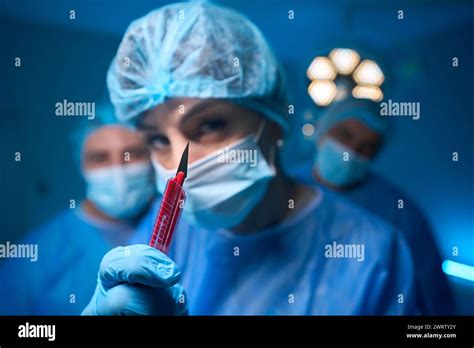 Woman Doctor Wearing Uniform And Gloves Showing Scalpel In Surgery Room Stock Photo Alamy