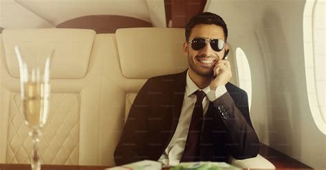 개인 제트기에 탑승한 젊은 행복한 부자가 샴페인과 현금으로 유로를 들고 테이블에 앉아 전화 통화를 하고 있다 사진 Unsplash의 사업 이미지