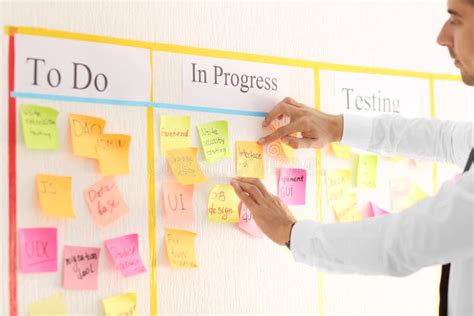 Man Attaching Sticky Note To Scrum Task Board In Office Stock Photo Image Of Kanban Caucasian