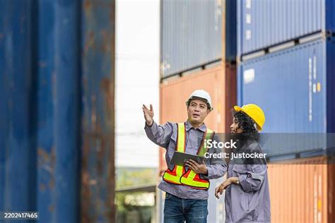 안전 장비를 착용한 여성 감독자와 안전모를 쓴 감독 작업자는 화물에서 컨테이너 상자를 적재하는 것을 확인하고 제어합니다 30 34세에 대한 스톡 사진 및 기타 이미지