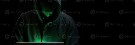 hacker without face in a hood holds a laptop on a dark background