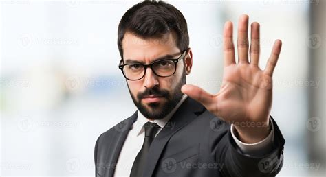 Serious Businessman In Suit And Glasses Holds Hand Up Signaling Stop