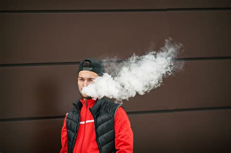 Vape 십 대입니다 블랙 캡 Vaping 현대 배경이 에서 반대는 전자 담배에에서 잘생긴 젊은 백인 남자의 초상화 20 24세에 대한 스톡 사진 및 기타 이미지 Istock
