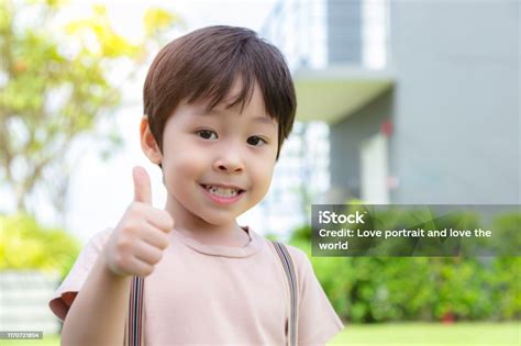웃는 얼굴로 엄지 손가락을 보여주는 귀여운 소년 사랑스러운 소년은 행복하고 편안한 느낌 그는 건강이 좋고 삶을 즐깁니다 어린 아이는 유치원 소년입니다 잘 생긴 소년은