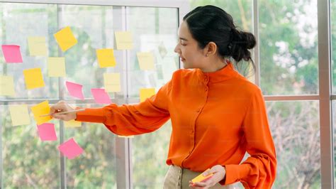 비즈니스 사람들은 사무실의 프로젝트 계획 보드에서 일하고 동료 친구와 대화하여 프로젝트 개발을 분석합니다 그들은 유리 벽에