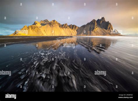 Reflection Of Vestrahorn Mountain Over Black Sand At Sunrise In Spring