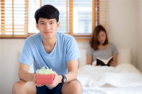 집에서 침실에서 사랑 깜짝 선물 상자에 아름 다운 젊은 아시아 커플 가족 기념일 을 즐기고 로맨틱 한 함께 아내와 남편 관계 발렌타인 데이 개념을 축 하 2명에 대한 스톡