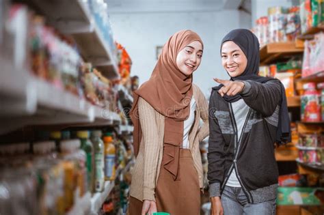 Dos Chicas Musulmanas Felices Con Dedos Apuntando Mientras Eligen Art Culos Imagen De Archivo