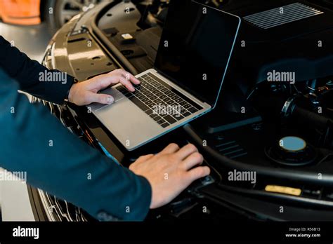 Partial View Of Businessman Checking Car Hood With Laptop With Blank