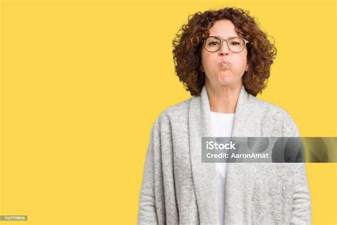 아름 다운 중간 거 대 수석 여 자가 웃 긴 얼굴을 가진 고립 된 배경 퍼 핑 뺨에 재킷과 안경을 착용 입에 공기 미친 표정으로 팽창 몸짓에 대한 스톡 사진 및 기타 이미지