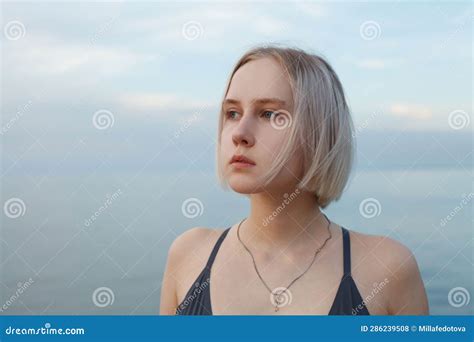 Portrait Of Blonde Woman Standing On The Background Of Blue Sea And
